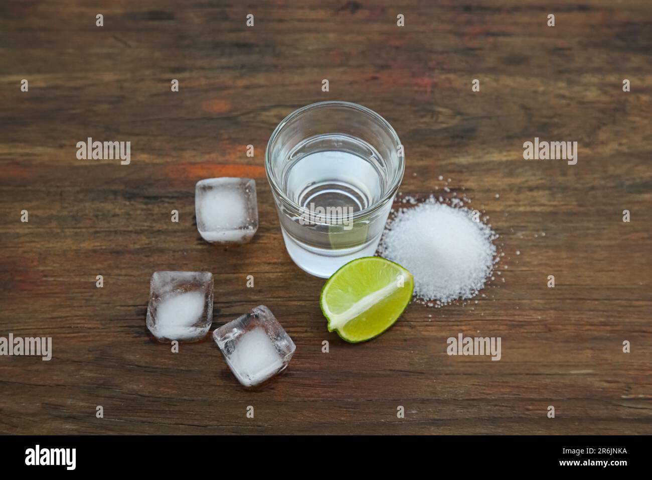 Mexican tequila shot with lime slice, ice cubes and salt on wooden ...