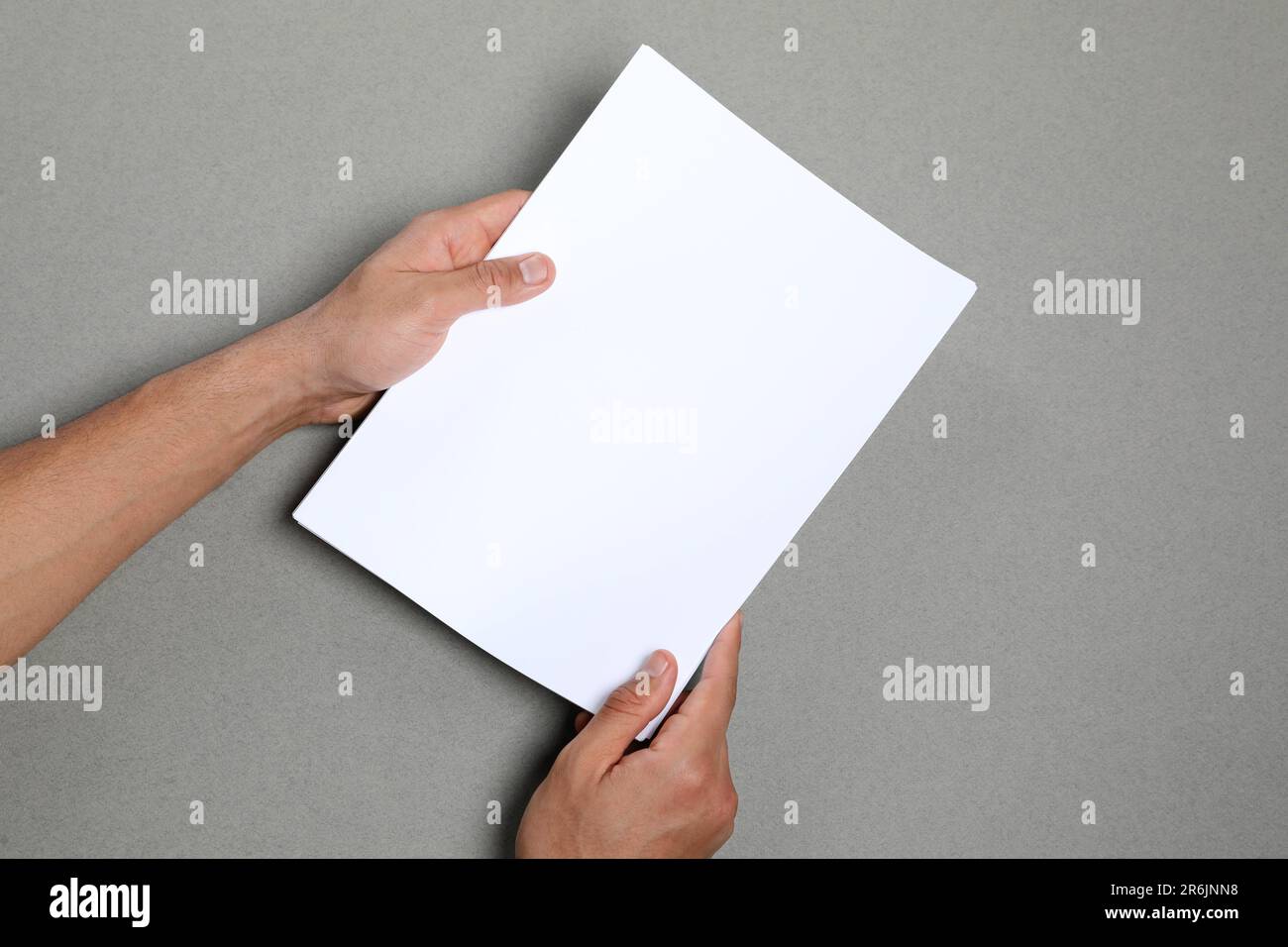 Man holding sheets of paper on grey background, closeup. Mockup for ...