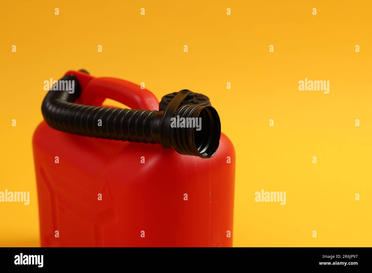Red plastic canister with tube on orange background, closeup. Space for ...