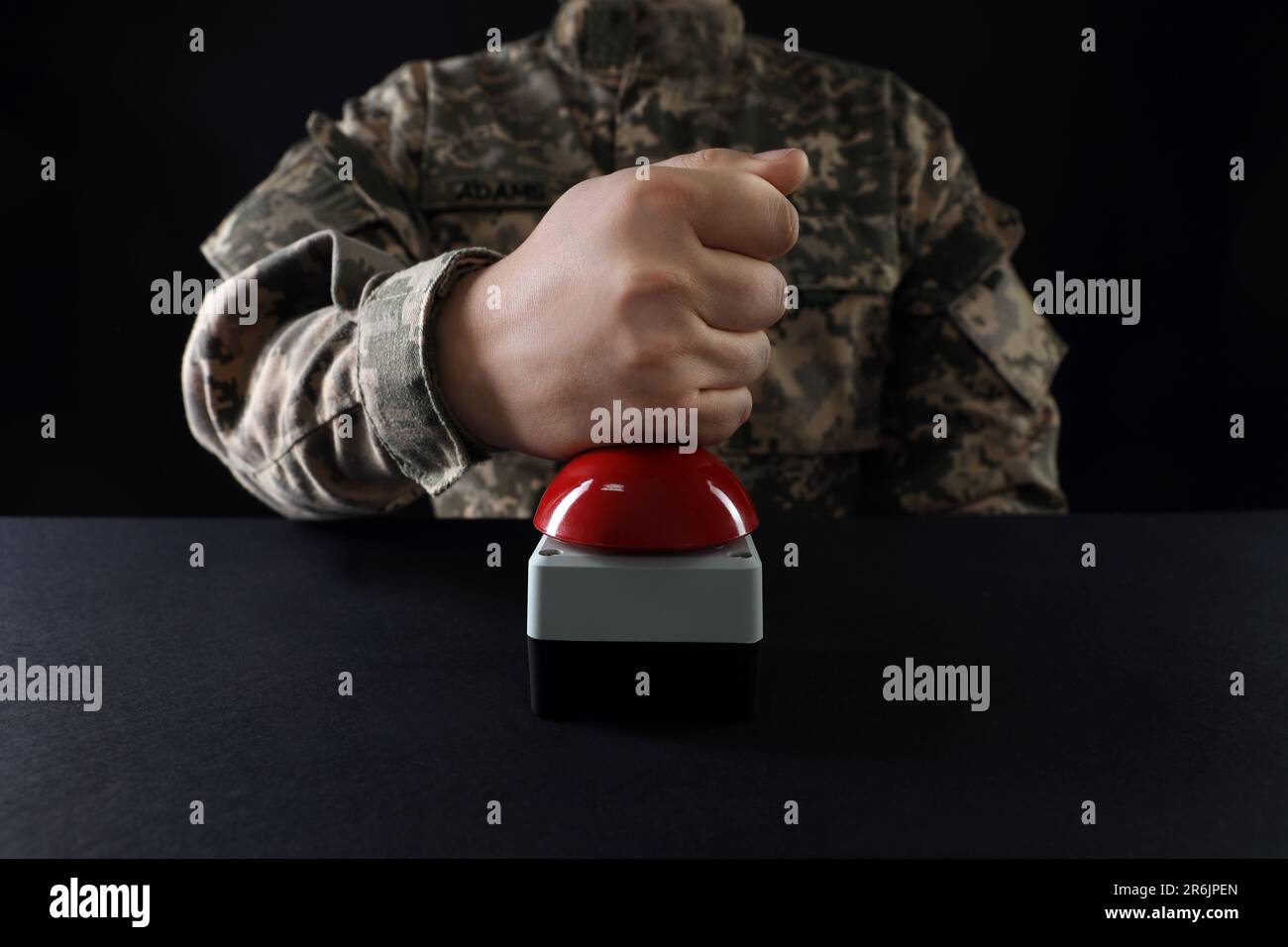 Serviceman pressing red button of nuclear weapon at black table ...