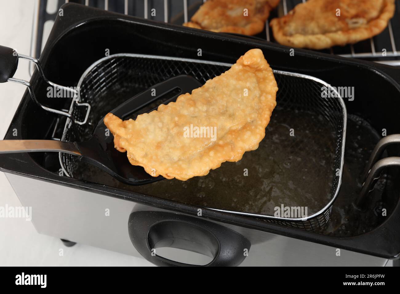 Spatula with delicious fried chebureki over deep fryer, above view ...