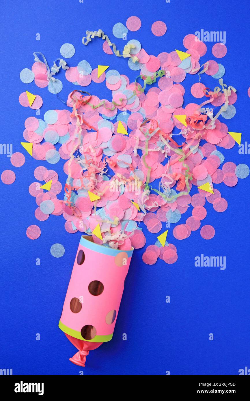 Colorful confetti and streamers bursting out of party cracker on blue ...