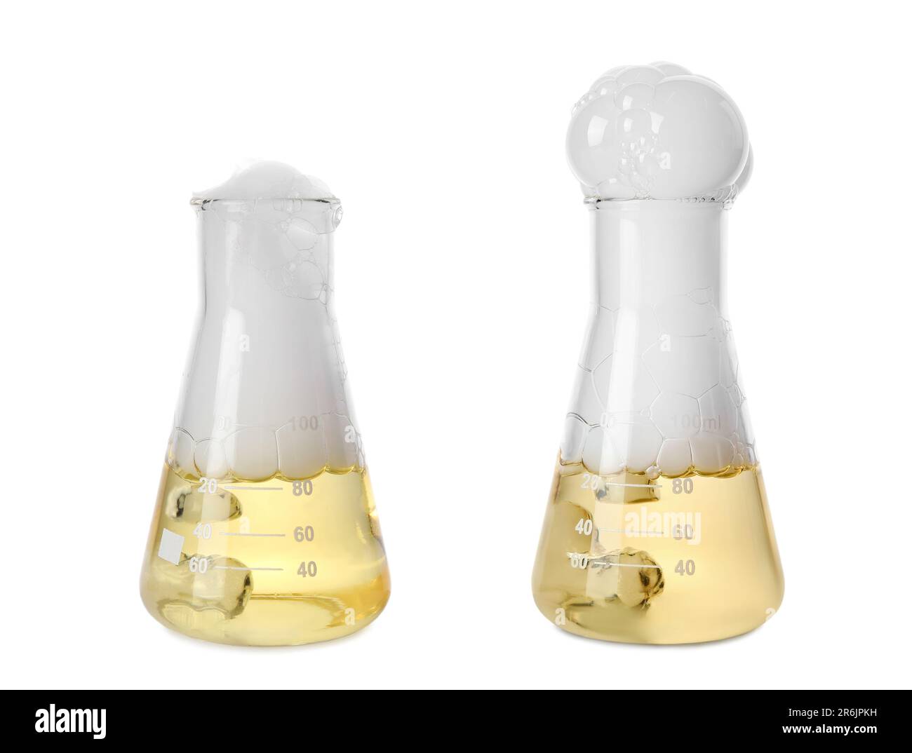 Laboratory flasks with yellow liquid and foam on white background ...