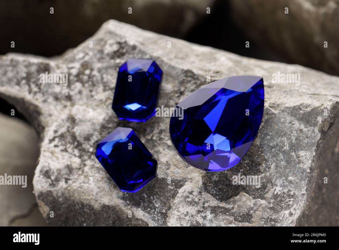 Three beautiful blue gemstones for jewelry on stone surface, closeup ...