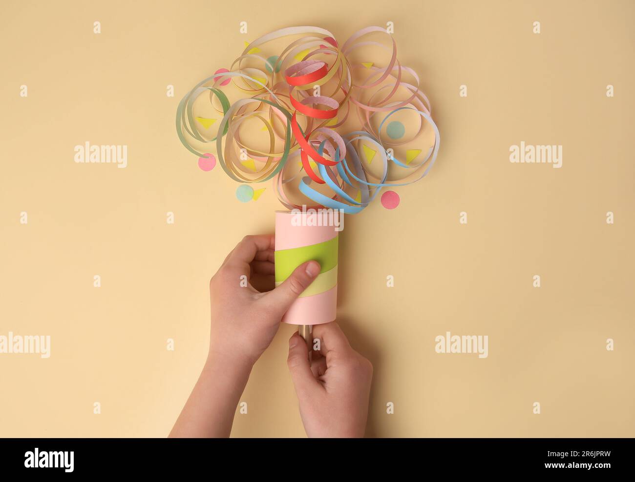 Woman holding party popper with serpentine and confetti on beige ...