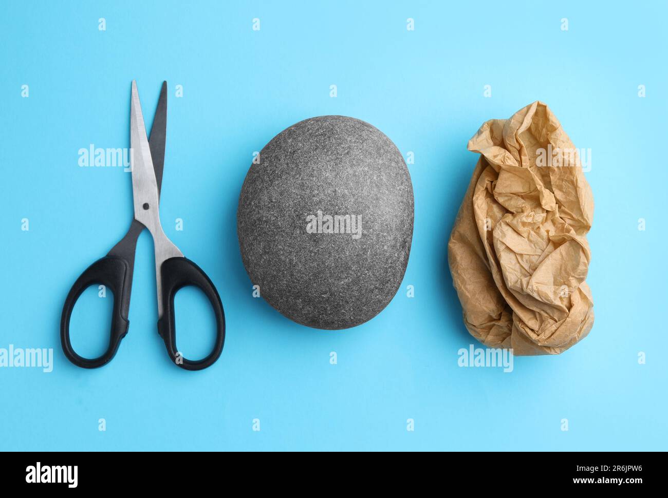 Rock, crumpled paper and scissors on light blue background, flat lay ...