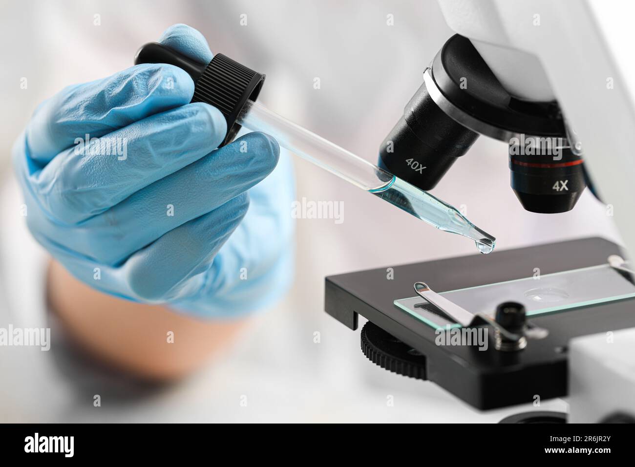 Scientist working with light blue liquid and microscope, closeup Stock ...