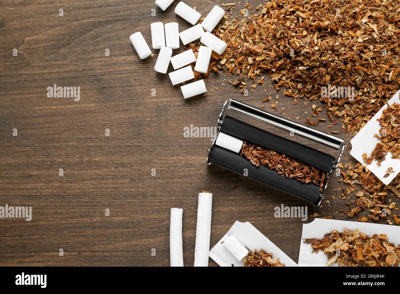 Flat lay composition with roller and tobacco on wooden table, space for ...