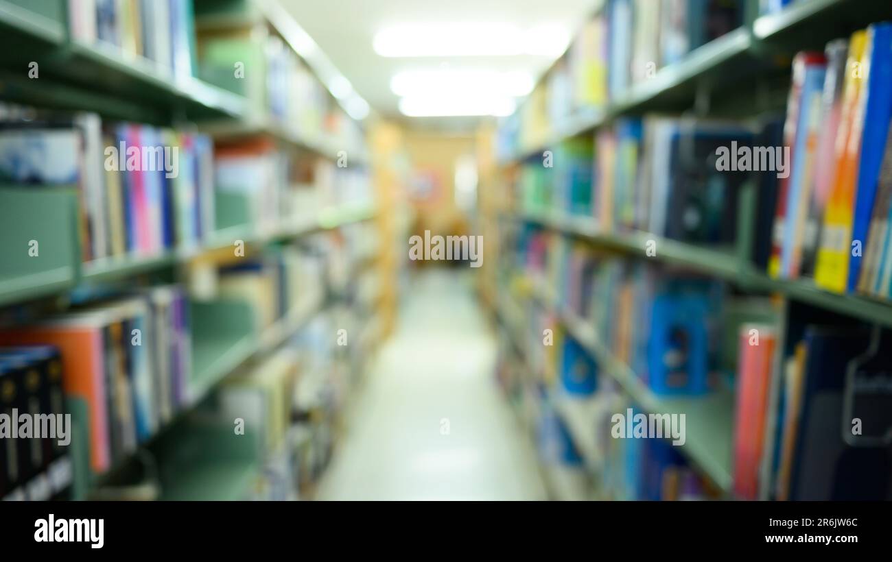 Blurred public library interior with aisle of bookshelf with textbooks ...