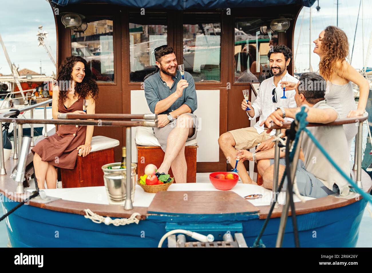 A group of friends relaxes on the back of the boat, enjoying an ...