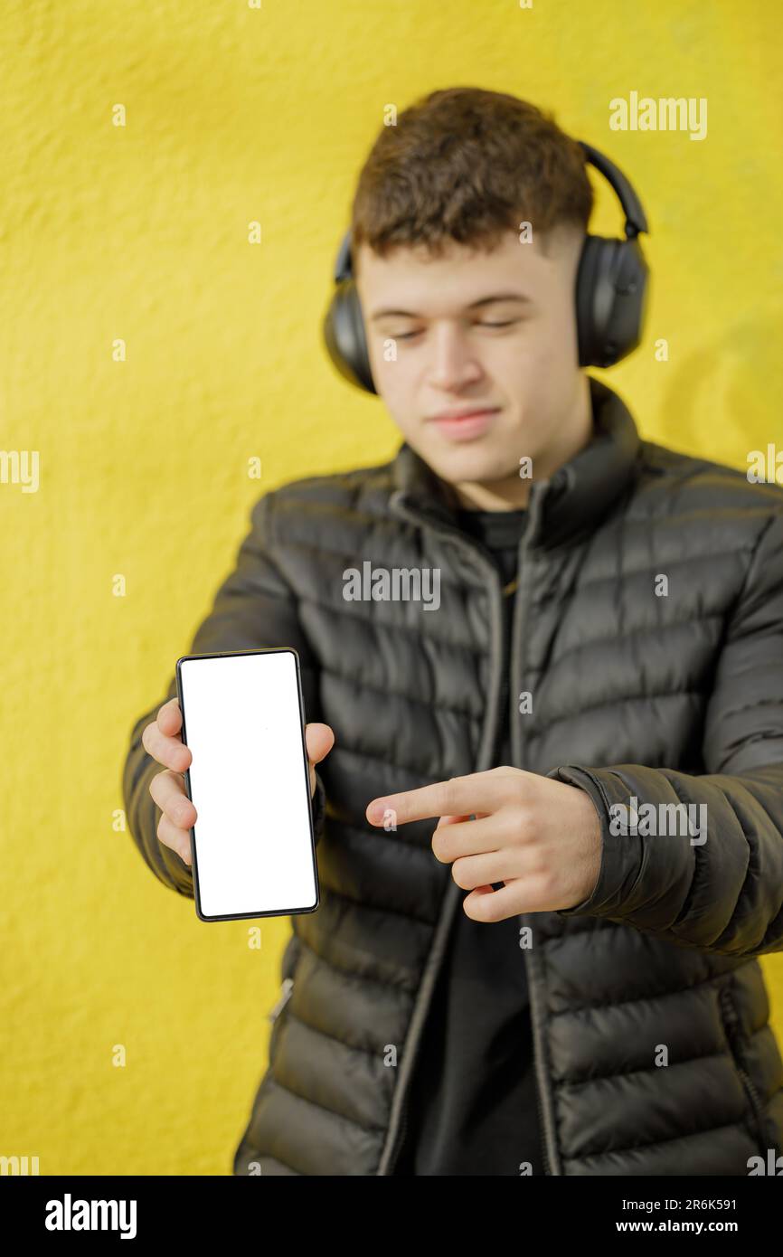 Caucasian boy with headphones out of focus shows the blank screen of ...