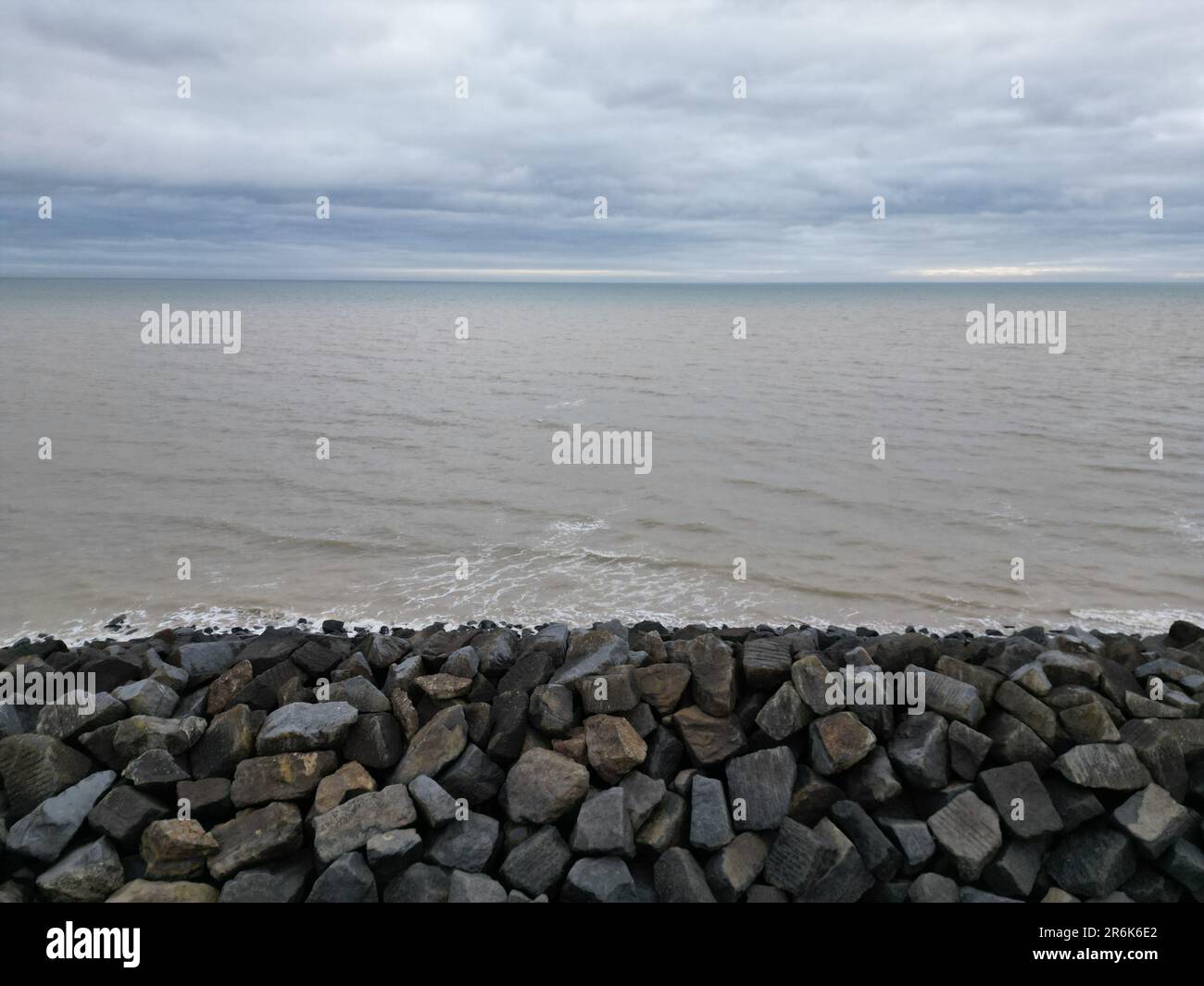 An expansive body of water featuring large rocks and pebbles scattered ...