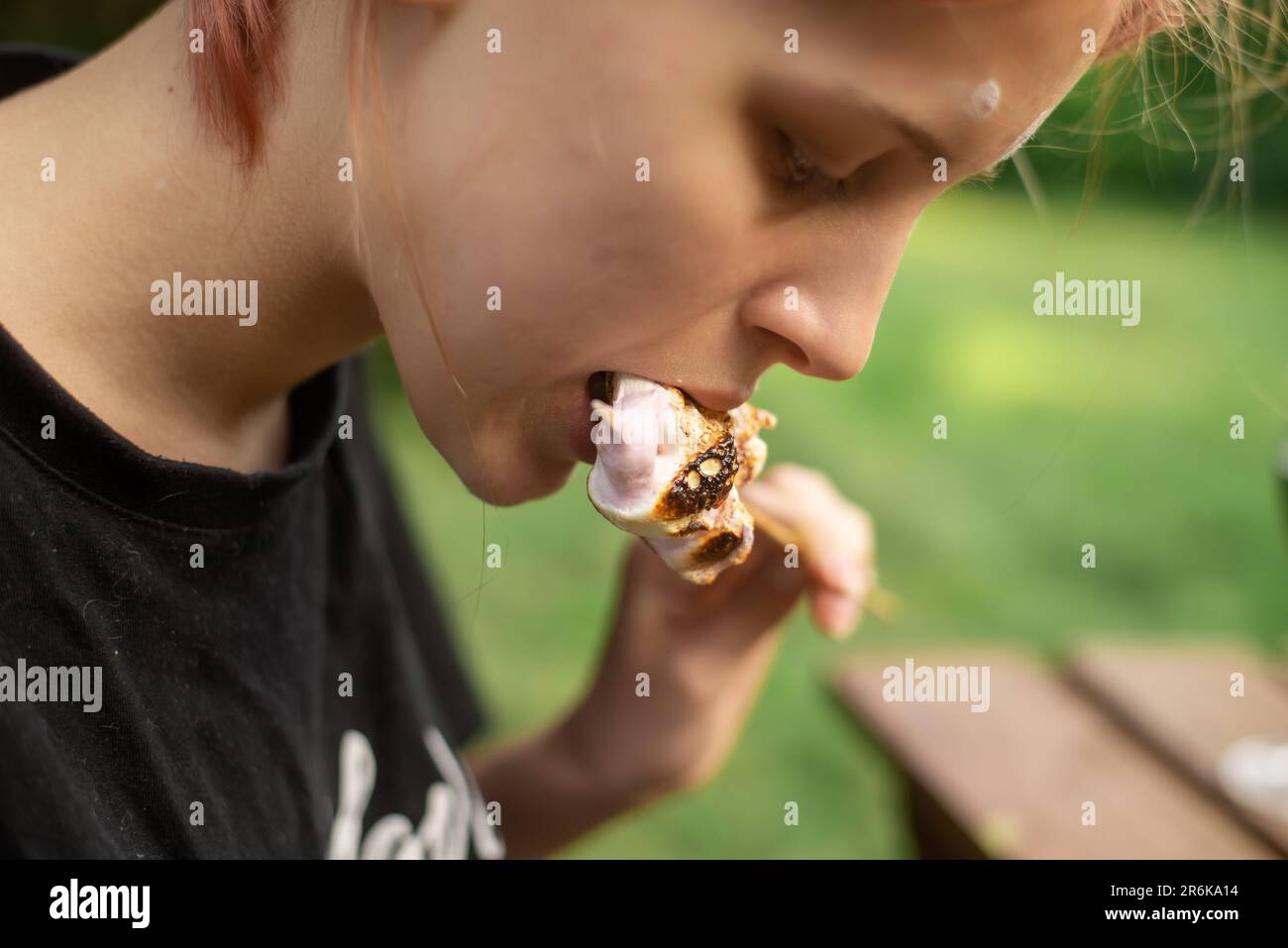 Girl eating marshmallow fried on the grill. Close-up. Sweet snack on ...