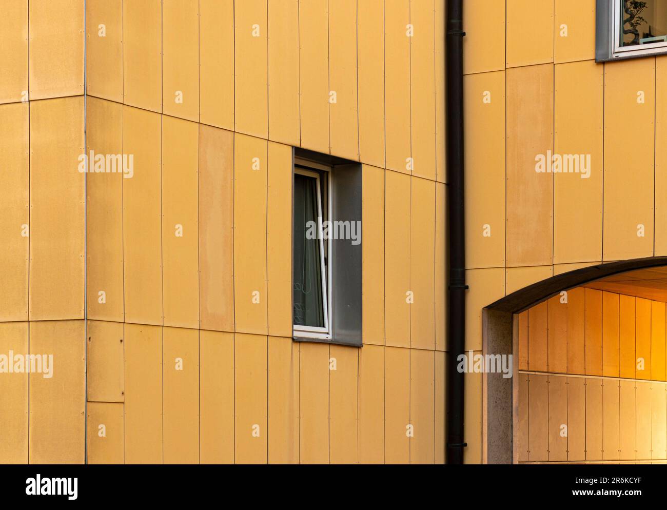 A tall modern yellow building with a window and archway Stock Photo - Alamy