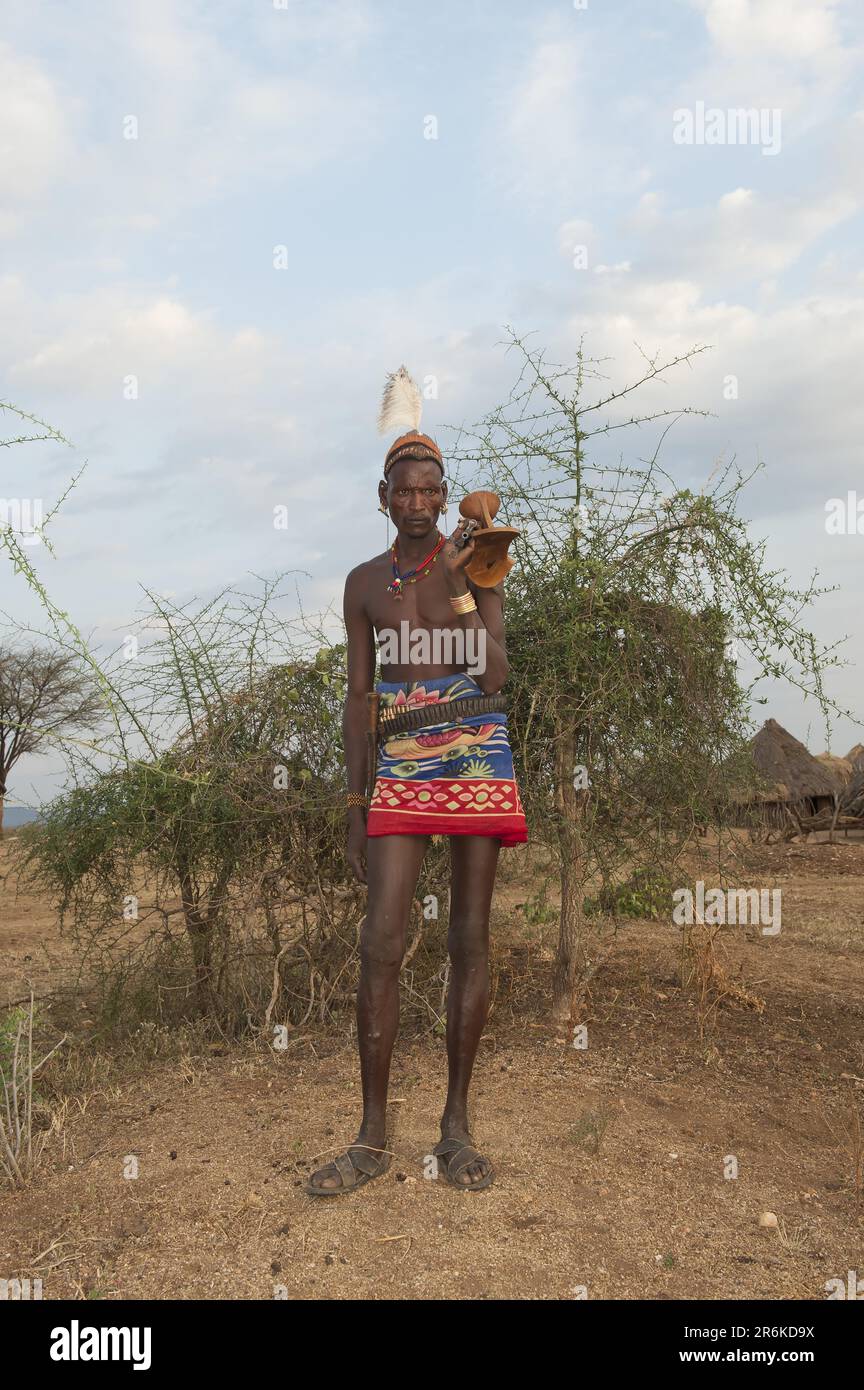 Hamar warrior with traditional clay hairstyle and feather, with rifle ...