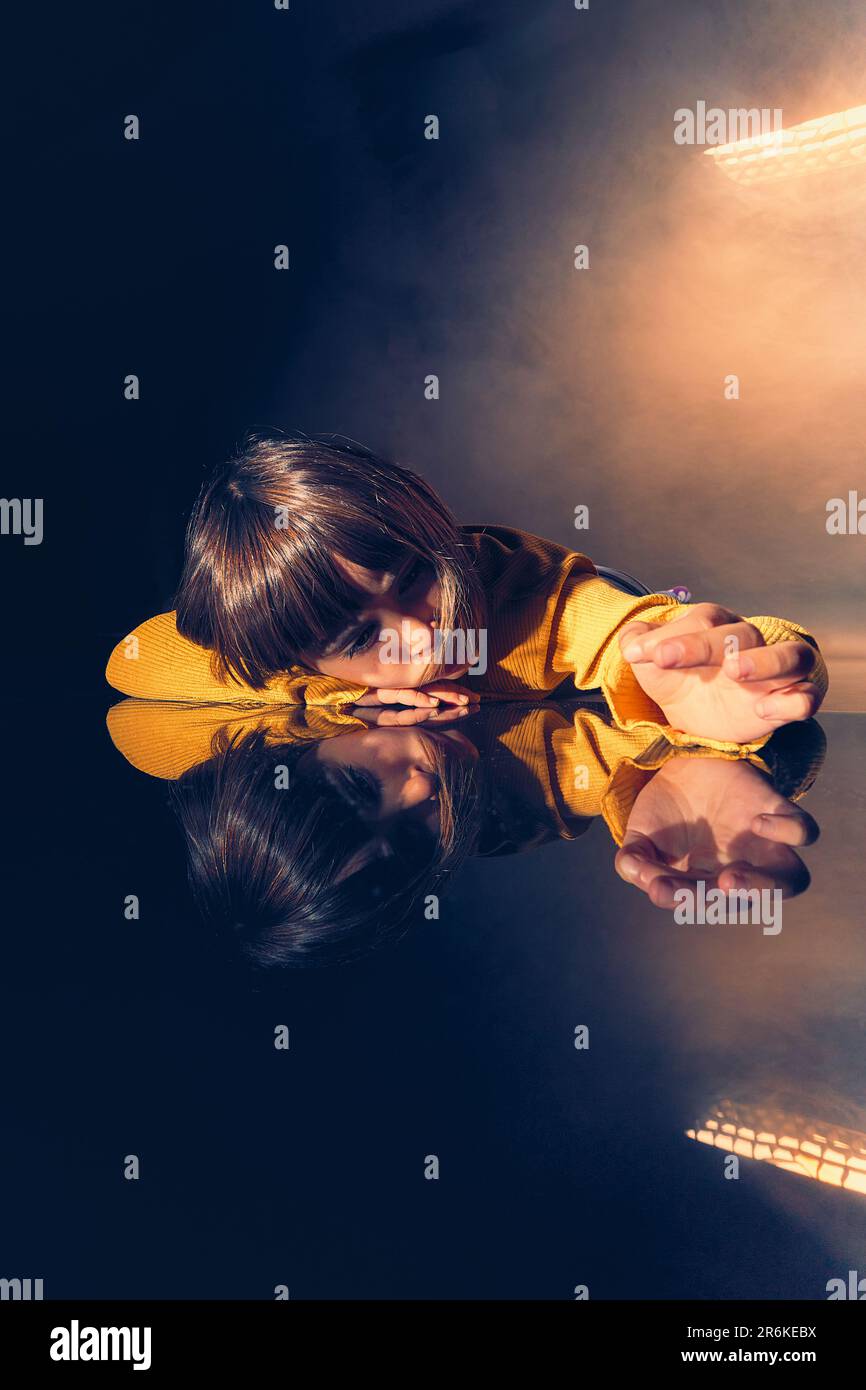 young girl with a depressed and sad face with her face reflected in a ...