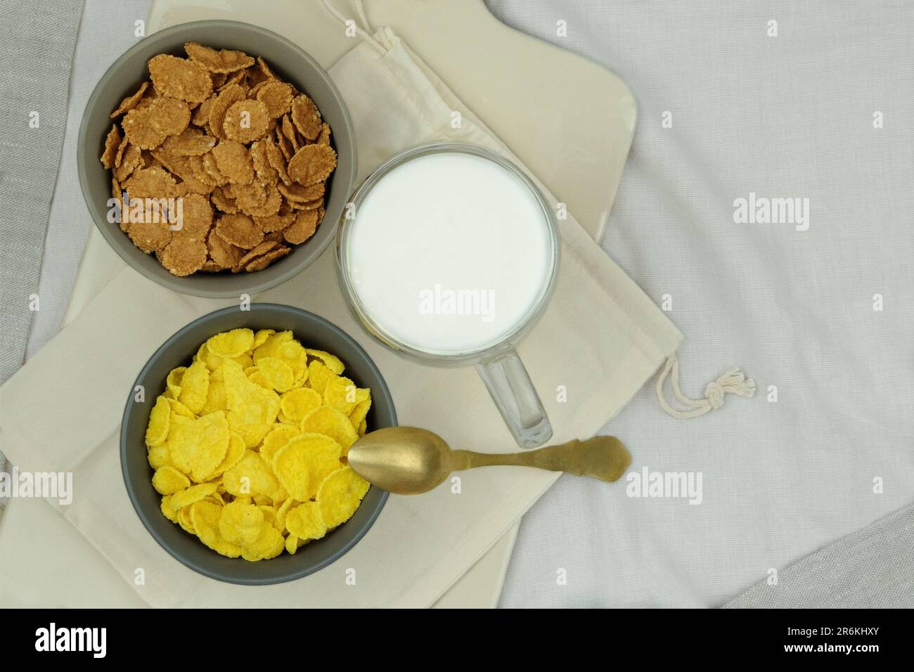Breakfast cereals, cornflakes in bowls and cup of milk on a light ...