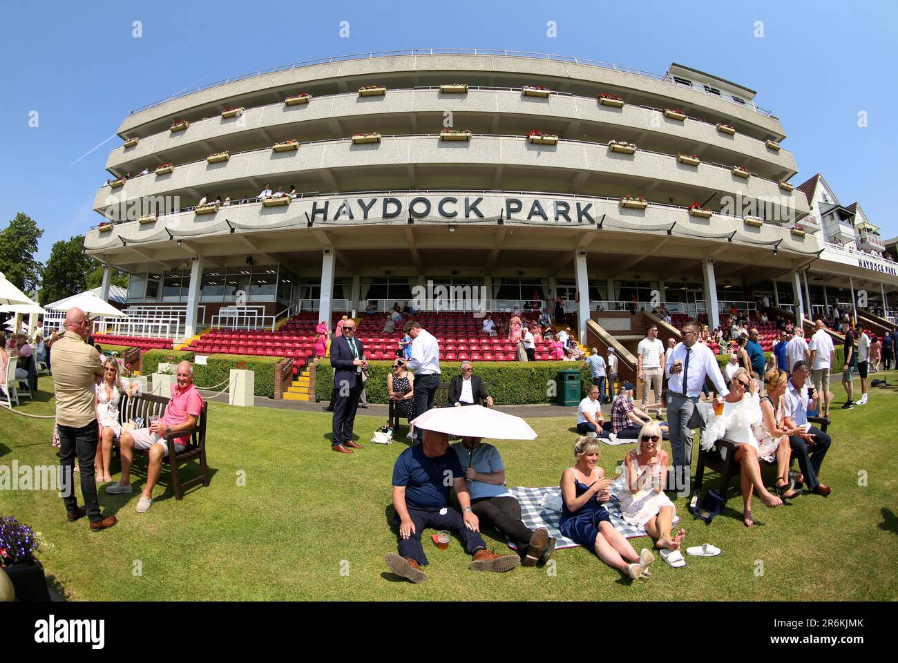 Racegoers Enjoy The Sun In Front Of The Grandstand Before The First Race At Haydock Park