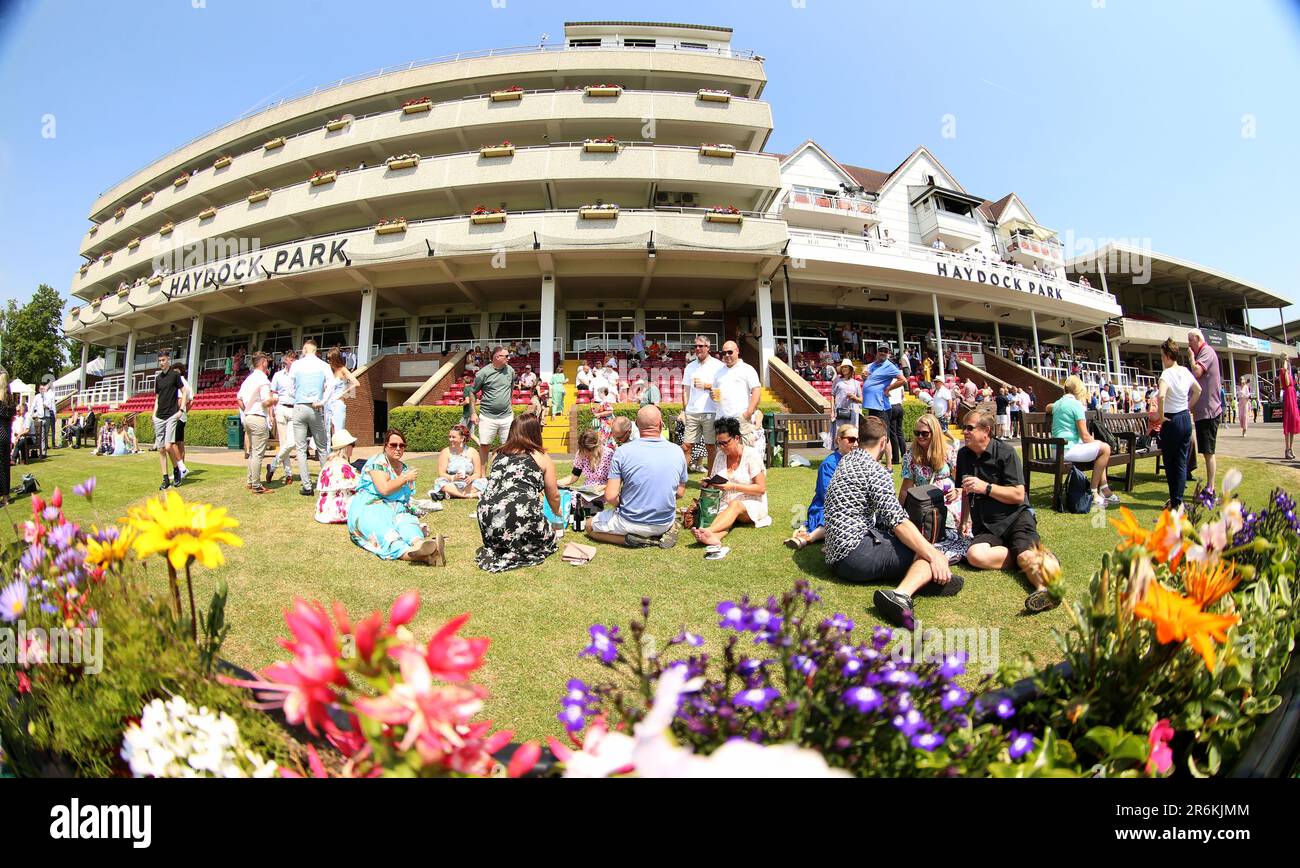 Racegoers enjoy the sun in front of the grandstand before the first ...