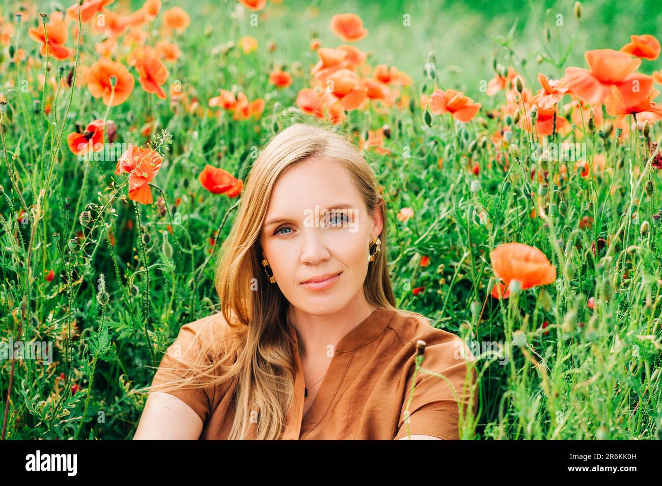 Outdoor portrait of attractive woman posing in poppy field Stock Photo ...