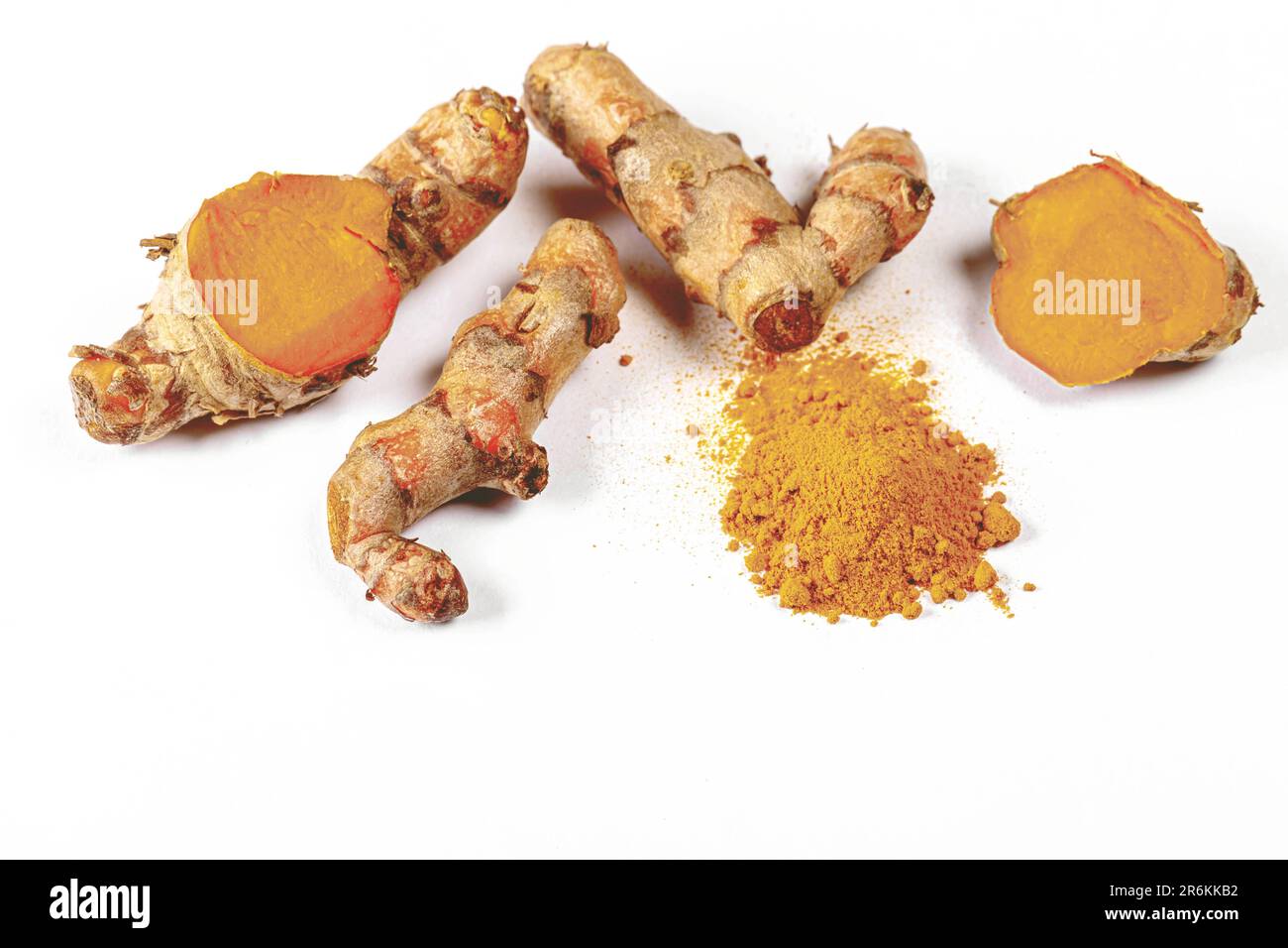 A pile of dried, yellow-orange tumeric root pieces lying on a flat ...