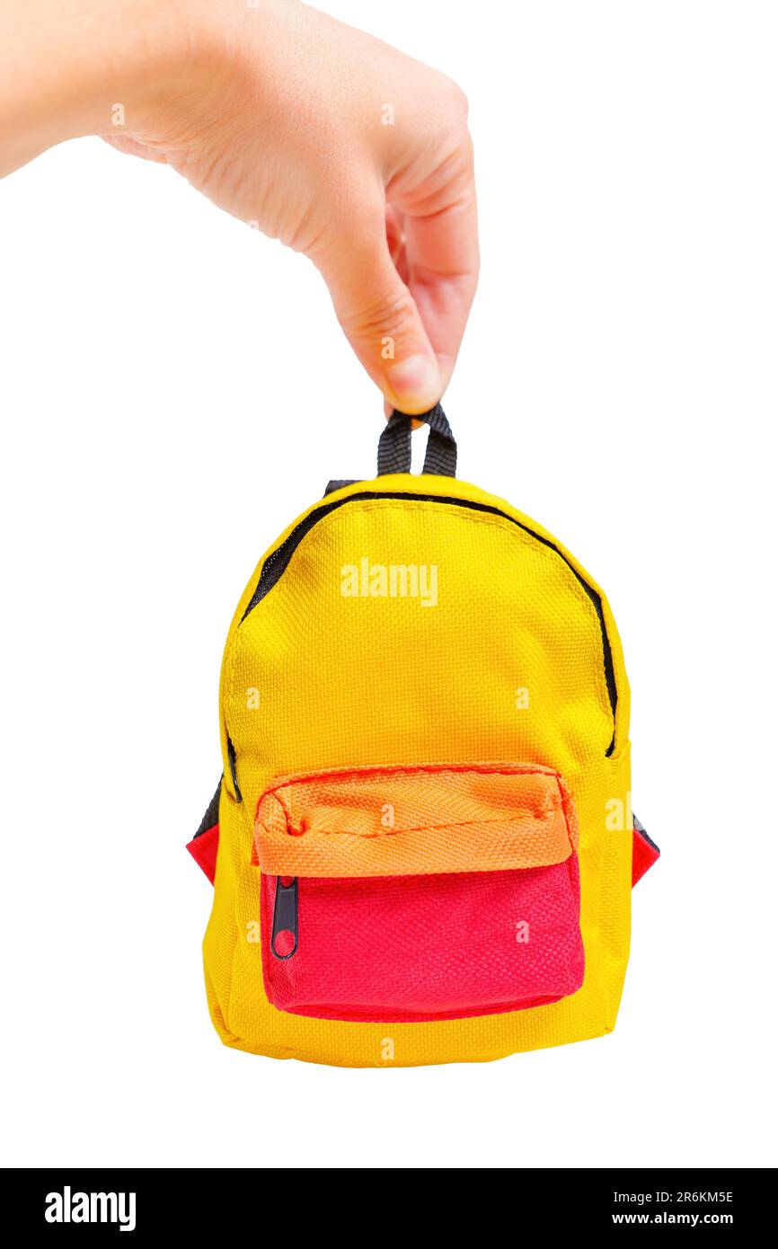 Hand pinch-holding a tiny yellow and red backpack isolated on white ...