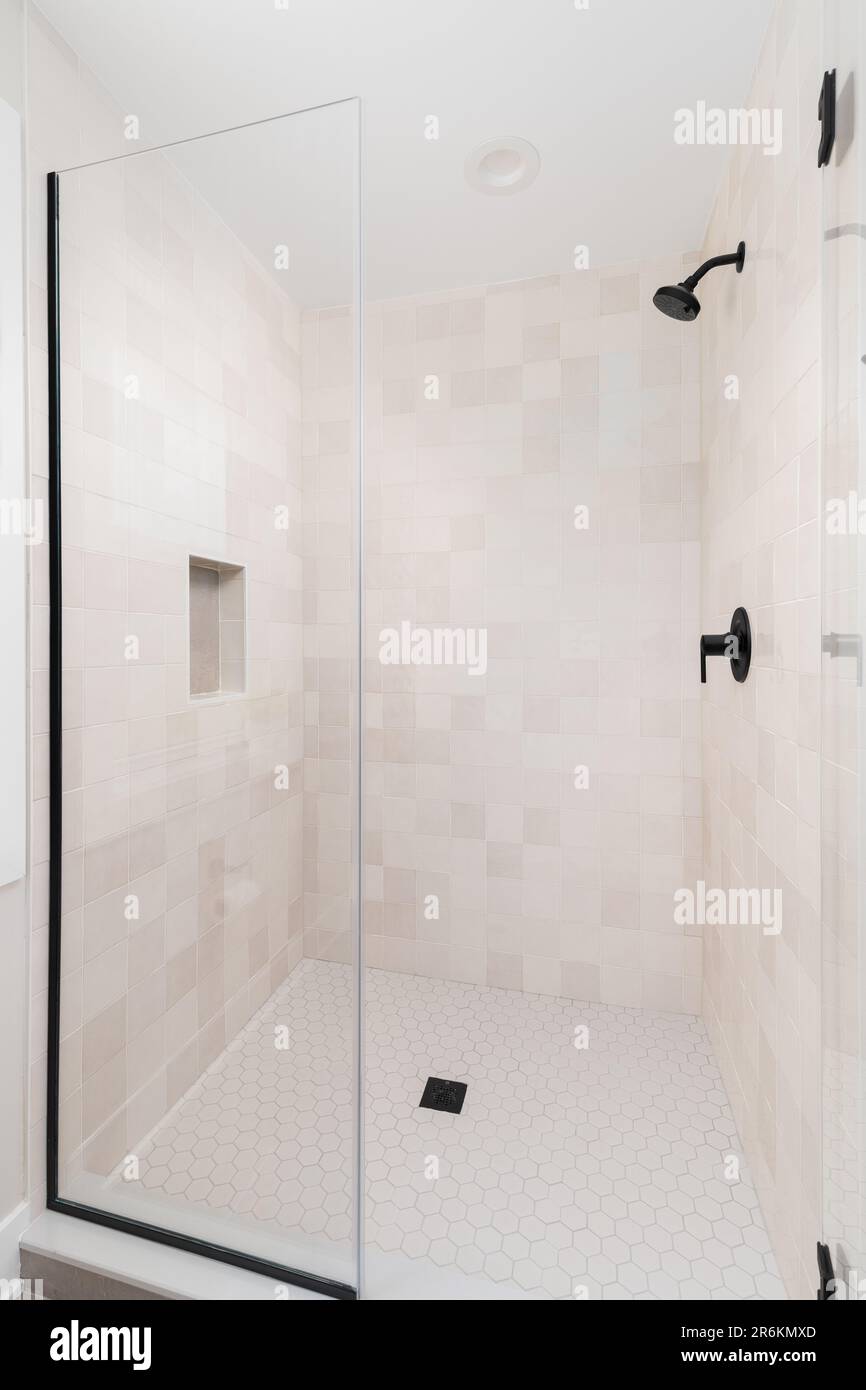 A shower with brown square tiles, black showerhead, and a hexagon tile ...
