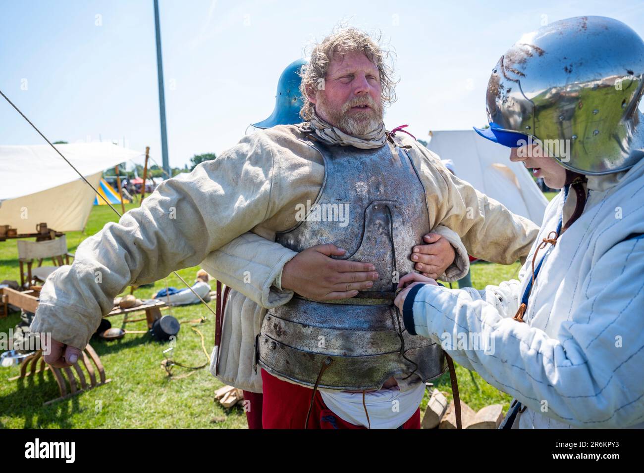 London, UK. 10 June 2023. A re-enactor is helped intop his armour ...