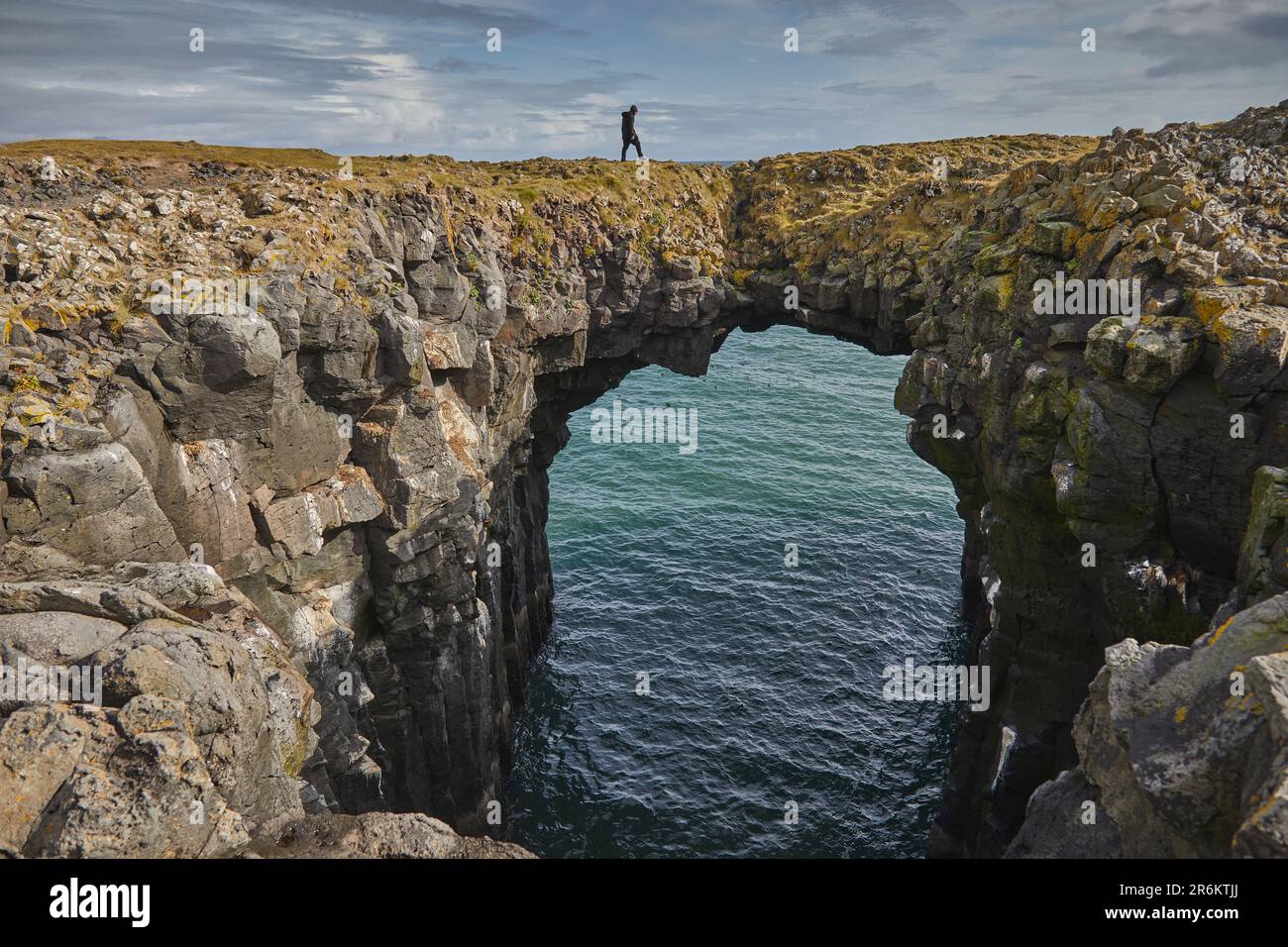 A basalt lava arch in the cliffs at the village of Arnastapi ...