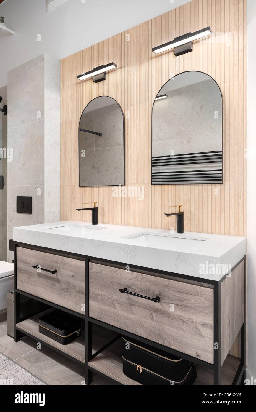 A modern bathroom with white oak wood slat paneling on the wall with ...