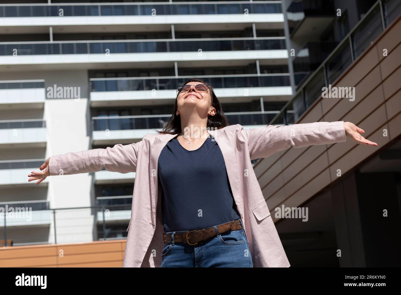Happy Mature Woman With Open Arms Enjoys Modern Residential Building ...