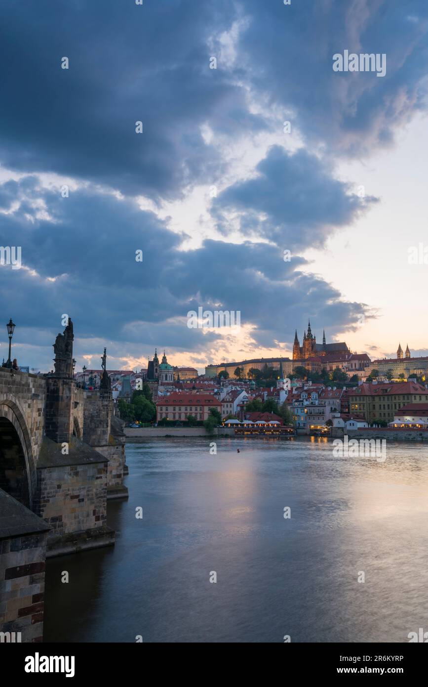 Prague Castle and Charles Bridge on Vltava River in city at twilight ...