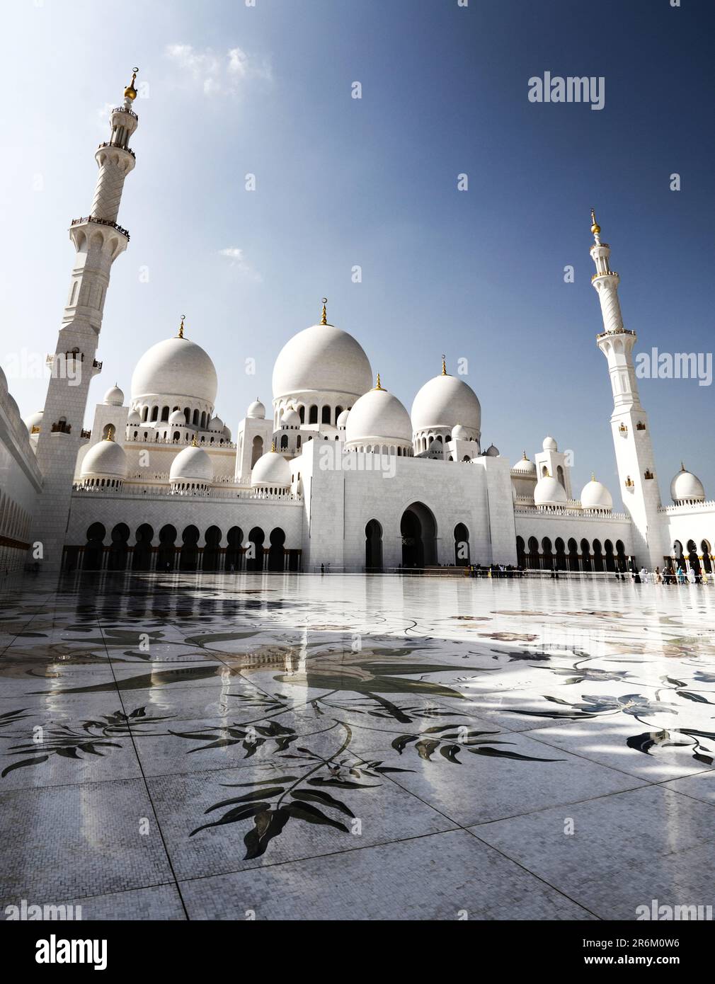 A stunning white marble mosque stands out against a blue sky background ...
