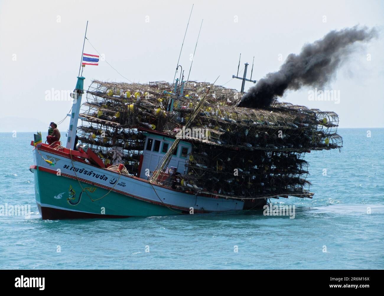 A boat sits in the middle of a body of water, filled to the brim with ...