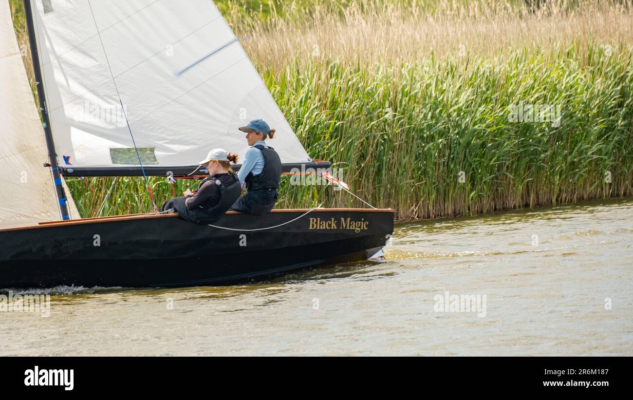 Two ladies racing a small wooden sail boat in the Three Rivers Race ...