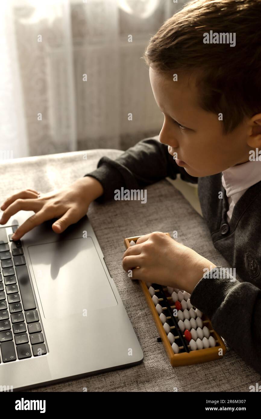 A 10-year-old boy learns mental math with a laptop and abacus Stock ...