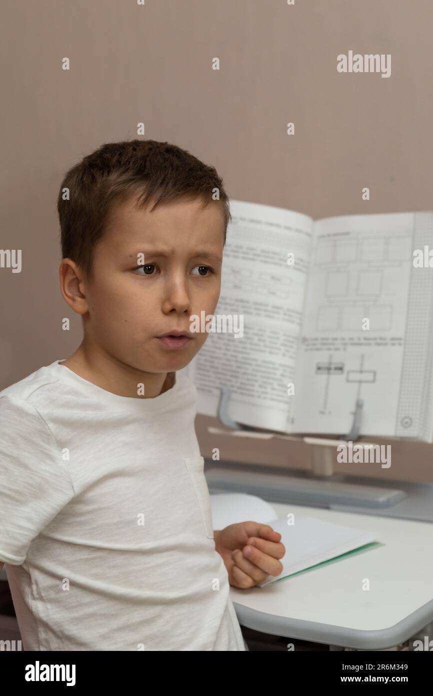 10-year-old schoolboy does homework, learns, thoughtfully memorizes new ...
