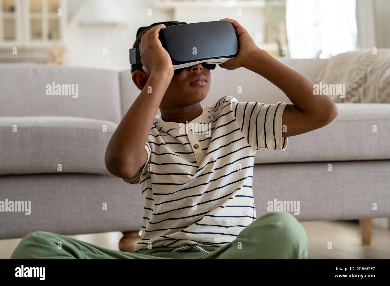 Obsessed child black boy experiencing 3D virtual reality in VR goggles ...