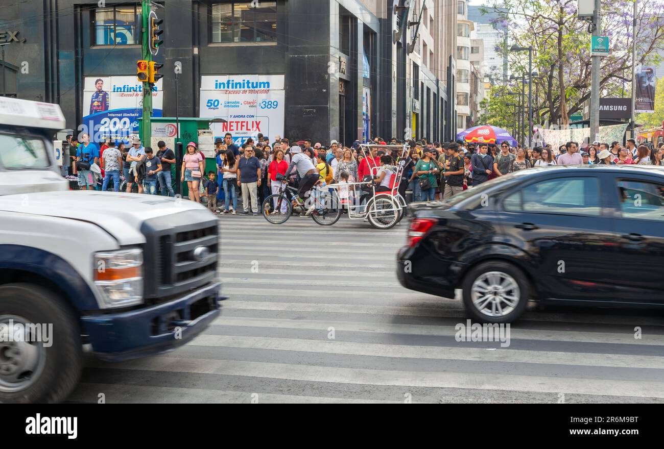Large crowd of people waiting to cross busy road in city centre, Mexico ...