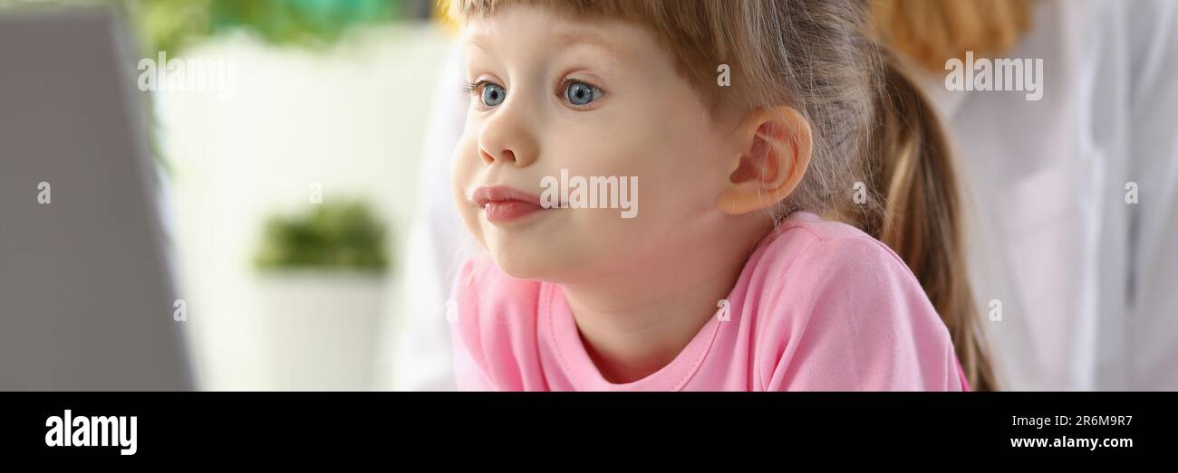 Beautiful little girl child carefully looks at monitor screen Stock ...