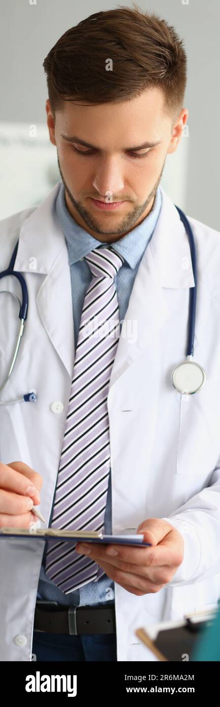 Male doctor filling out patient medical form in clinic Stock Photo - Alamy