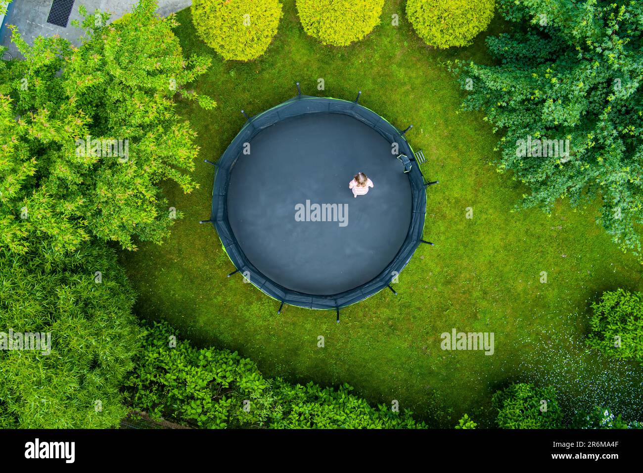 Aerial top-down view of a teenage girl jumping on a trampoline in a ...