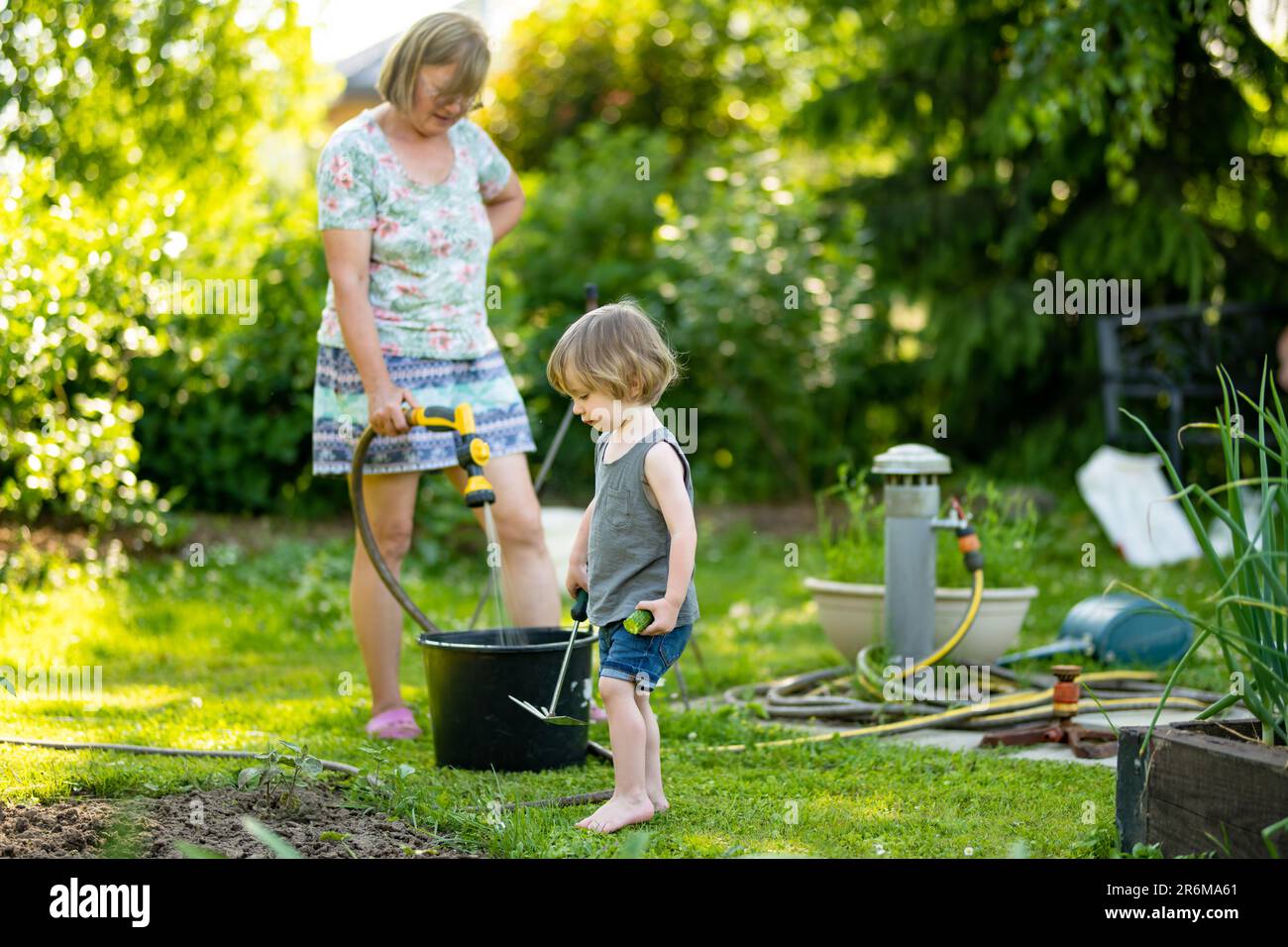 Cute toddler boy helping in the garden on sunny summer day. Child ...