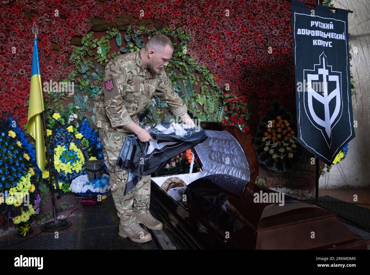 A fighter of the Russian Volunteer Corps puts the unit flag on a coffin ...
