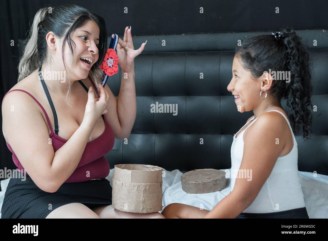 young latina mother showing her little daughter a flower headband Stock ...