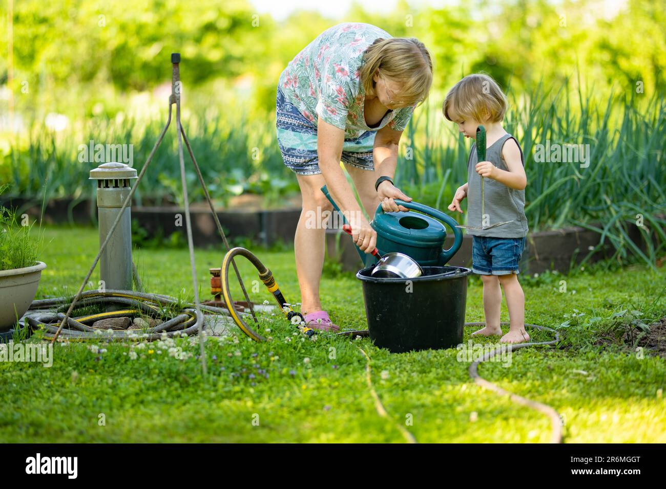 Cute toddler boy helping in the garden on sunny summer day. Child ...