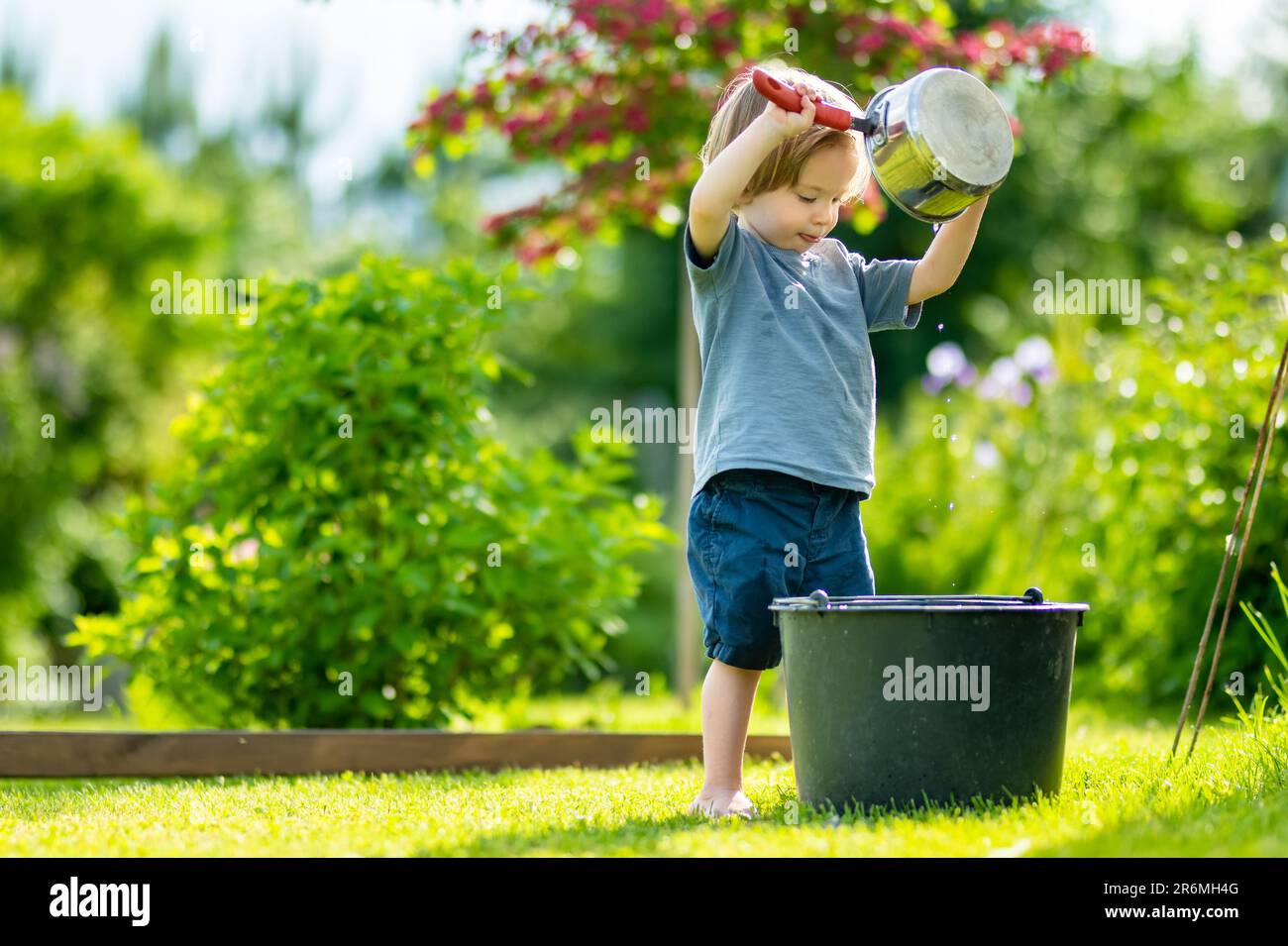 Cute blond little toddler playing with a cooking pot outdoors in the ...
