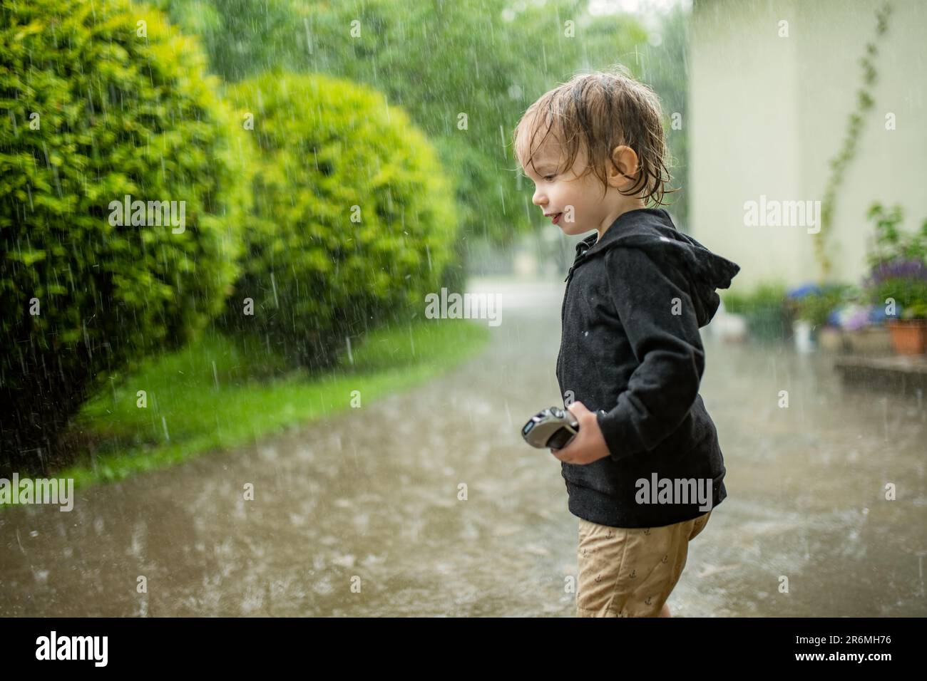 Adorable toddler boy having fun outdoors on rainy summer day. Child ...