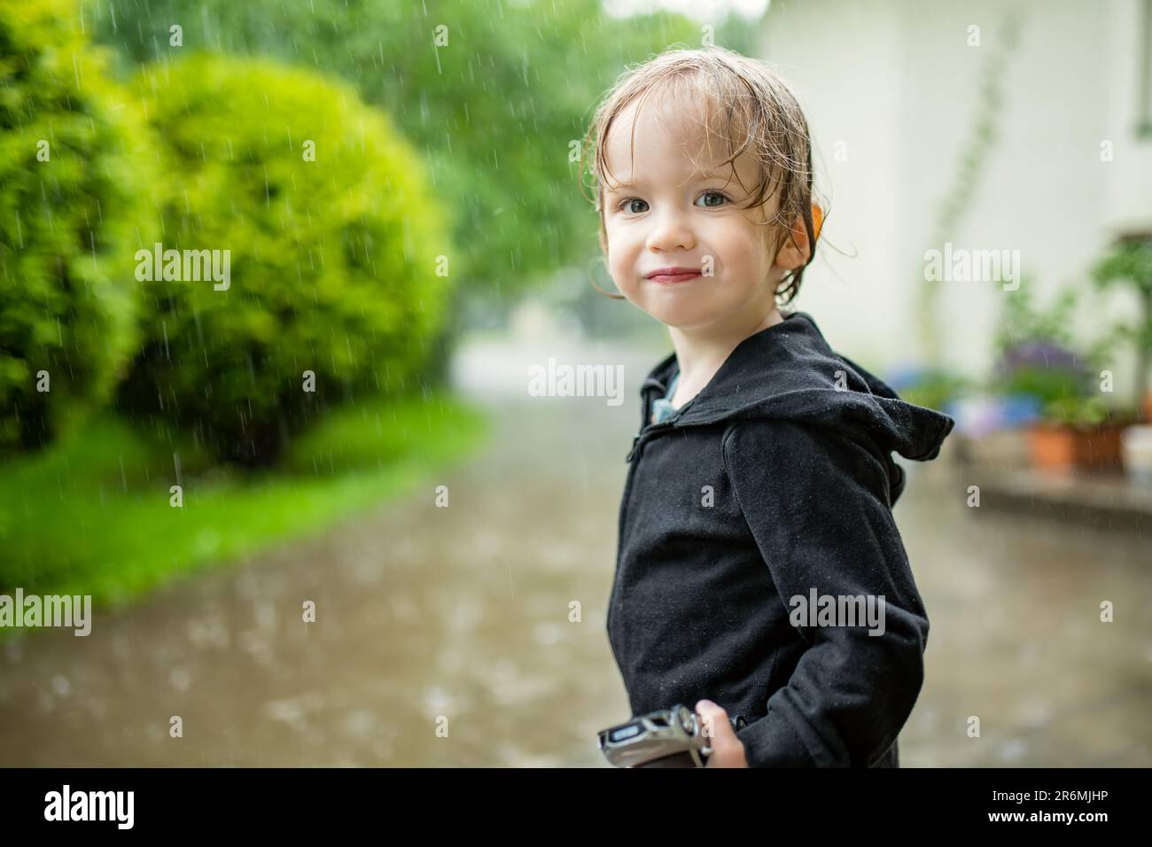 Adorable toddler boy having fun outdoors on rainy summer day. Child ...