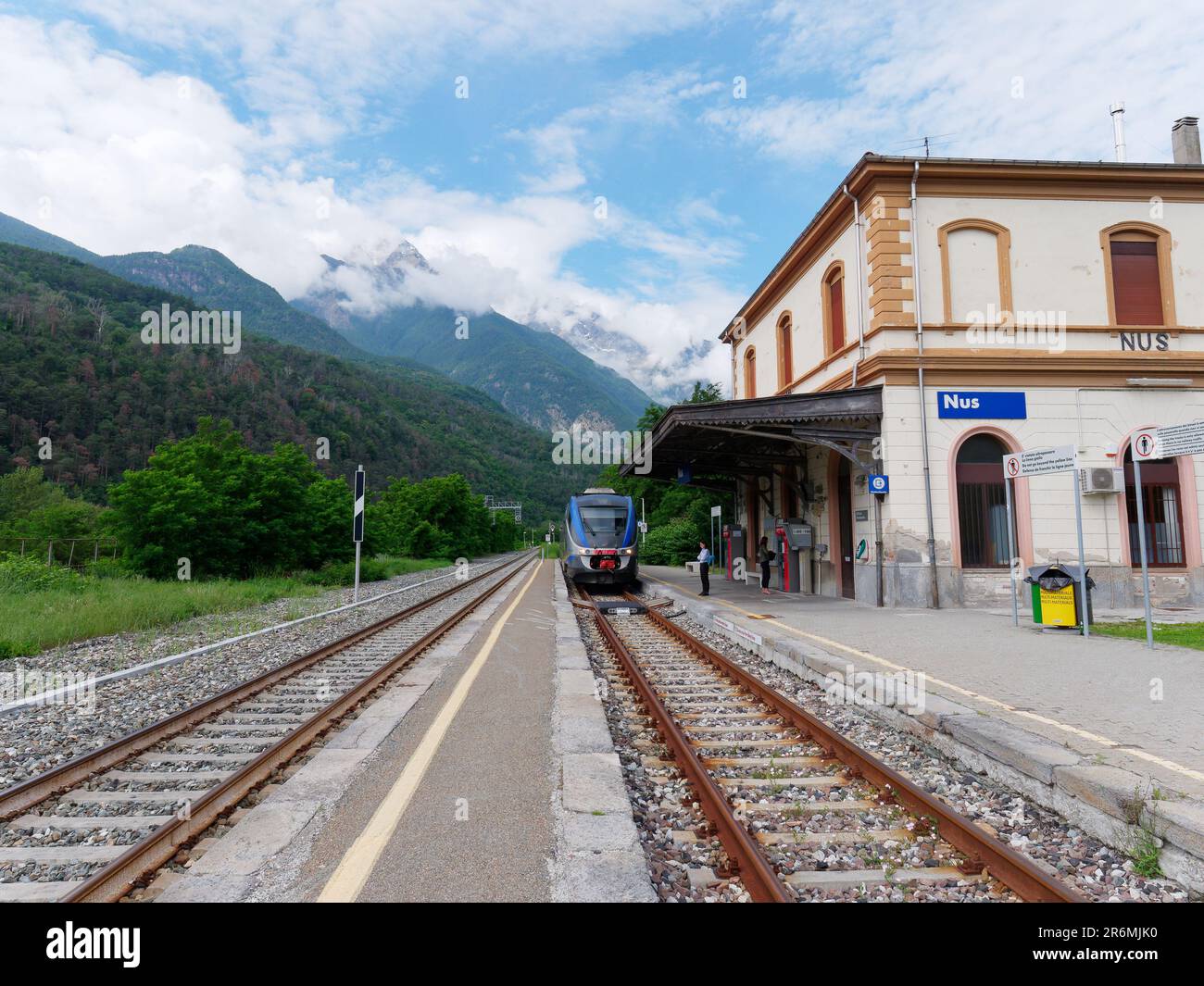 Official and train at the platform in Nus Train station, Aosta Valley ...